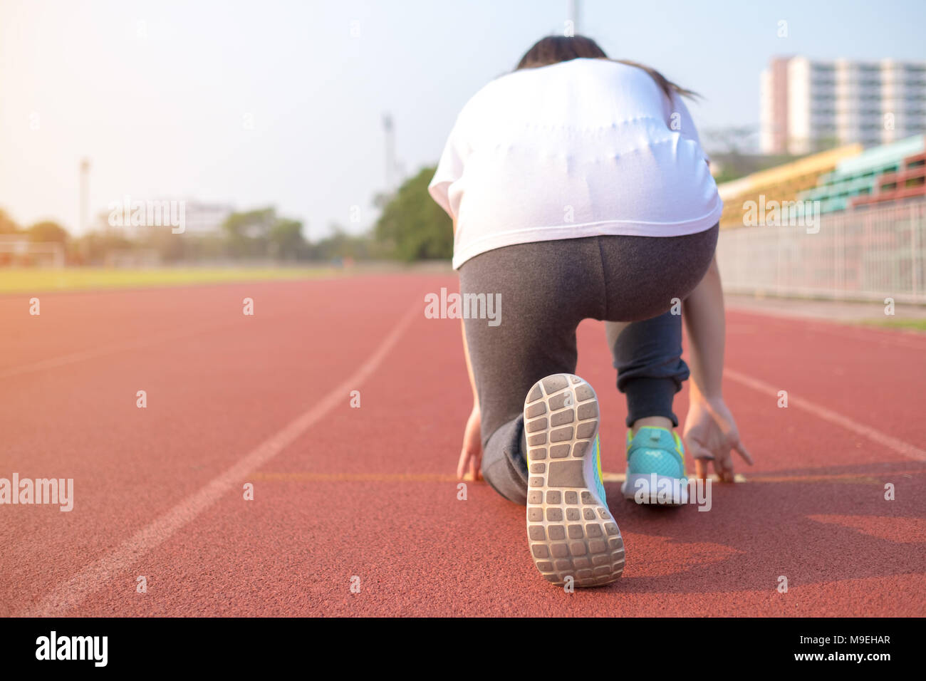 Rear view of young woman get ready to run on track, training and ...