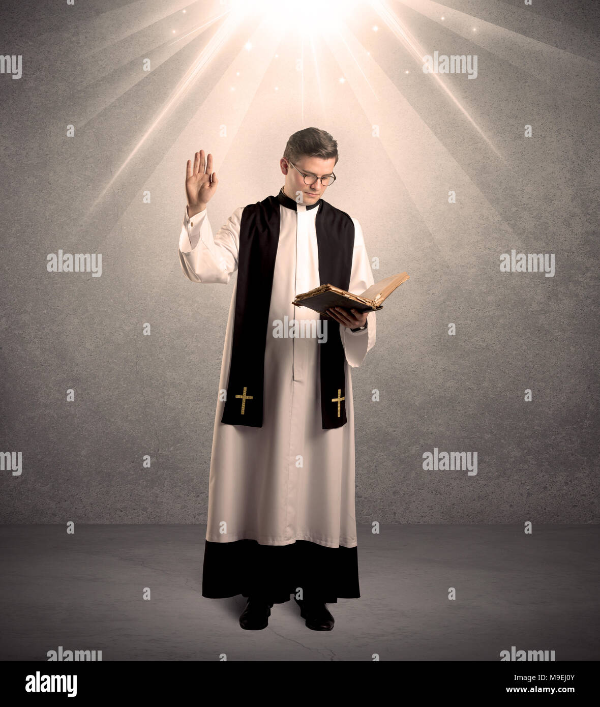 A male religious young priest in black and white dress giving his ...