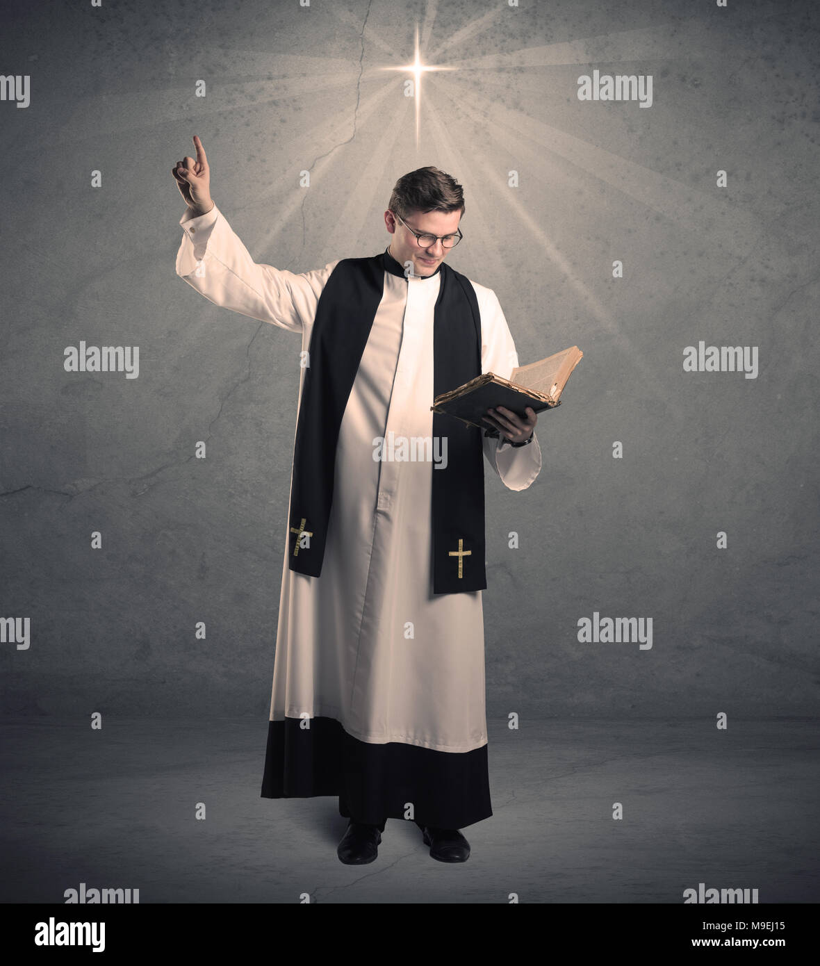 A young male priest in black and white giving his blessing in front of ...