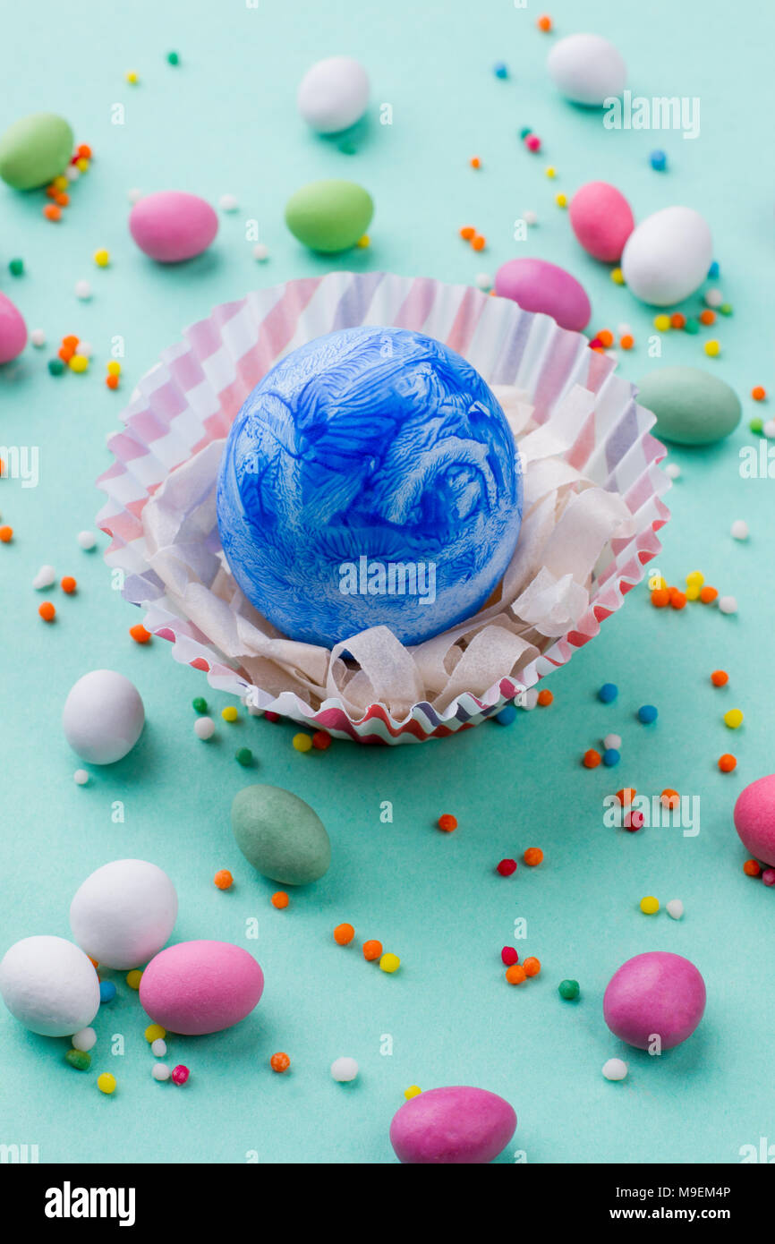 Easter egg and multicolored sweets. Blue Easter egg in paper wrapper ...
