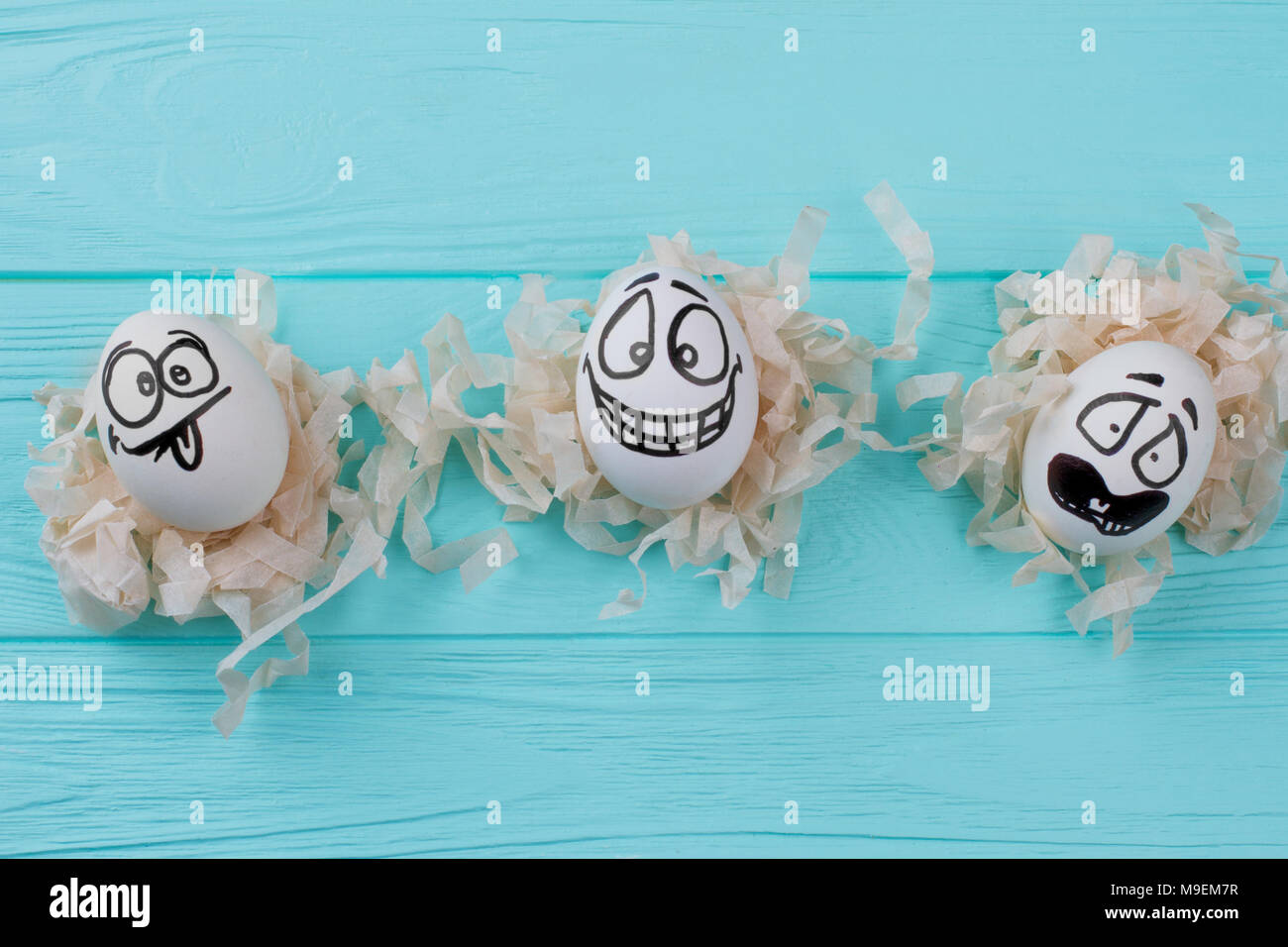 Funny Easter eggs with faces. Drawing faces on eggs, blue wooden ...