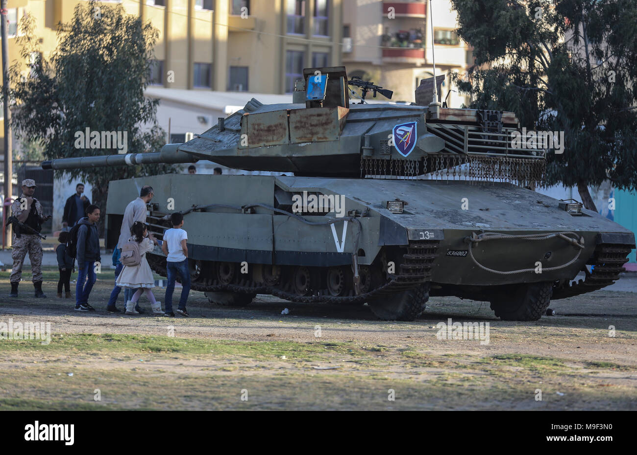 Palestinians walk past a life-size model of an Israeli Merkava tank ...