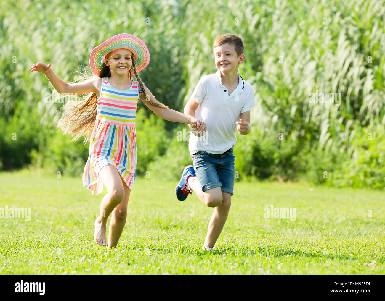 happy smiling little girl and boy running together holding hands in ...