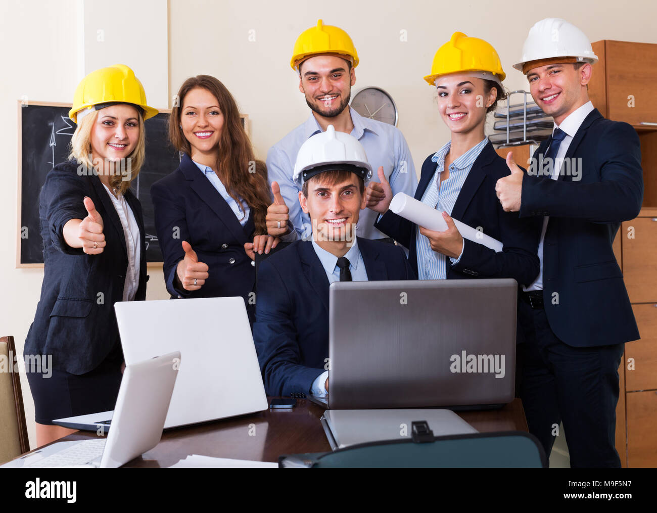 Professional planners with helmets posing at a architecture bureau ...