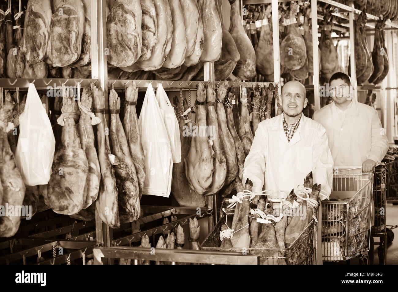 Mature butcher and his assistant with the jamon joints at the meat ...