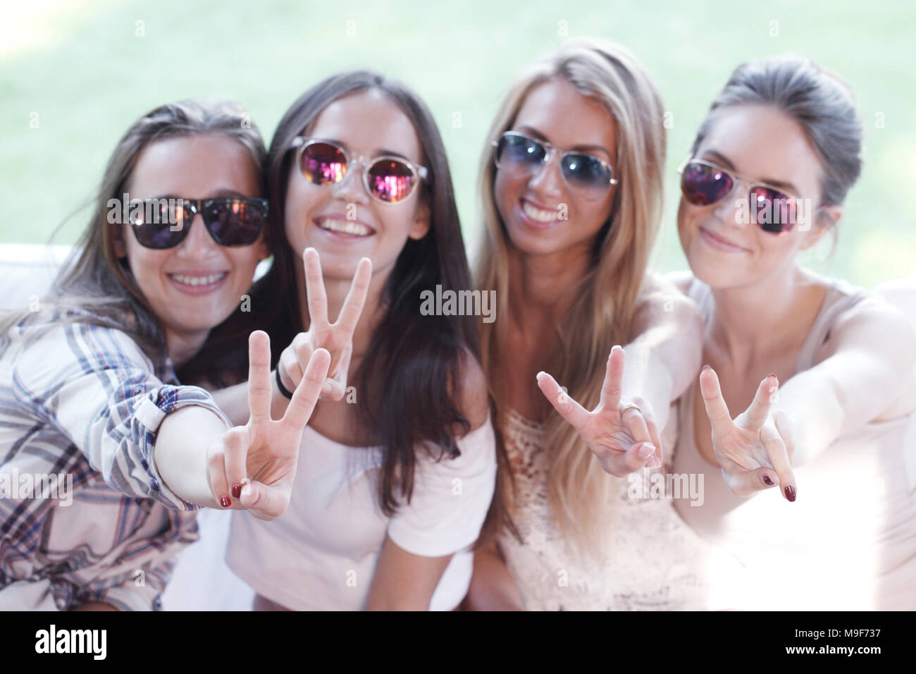 Happy smiling girlfriends showing a v hand sign Stock Photo - Alamy