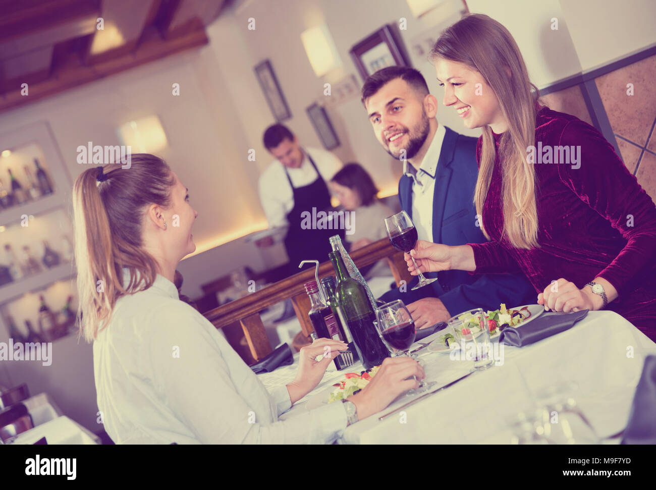 Glad positive smiling friendly meeting over dinner with wine in ...