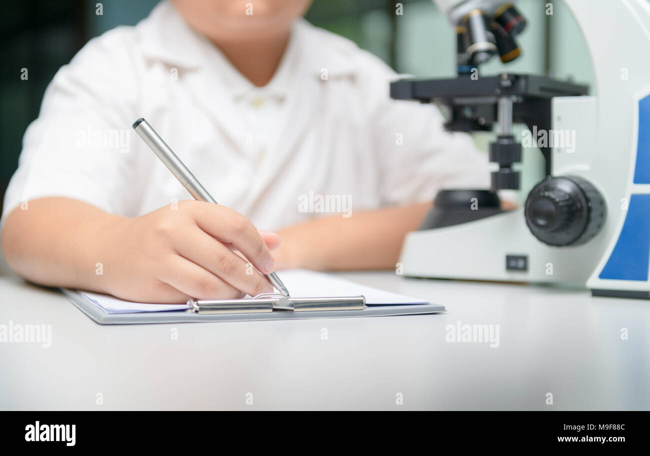 Project research. Little chemist boy writing on his clipboard while ...