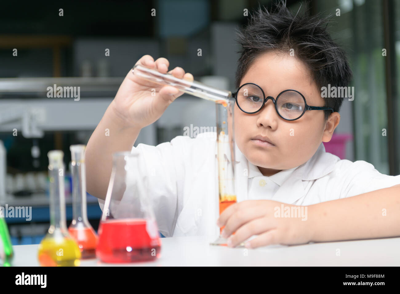 cute boy in lab coat making experiment with test tube in chemical ...