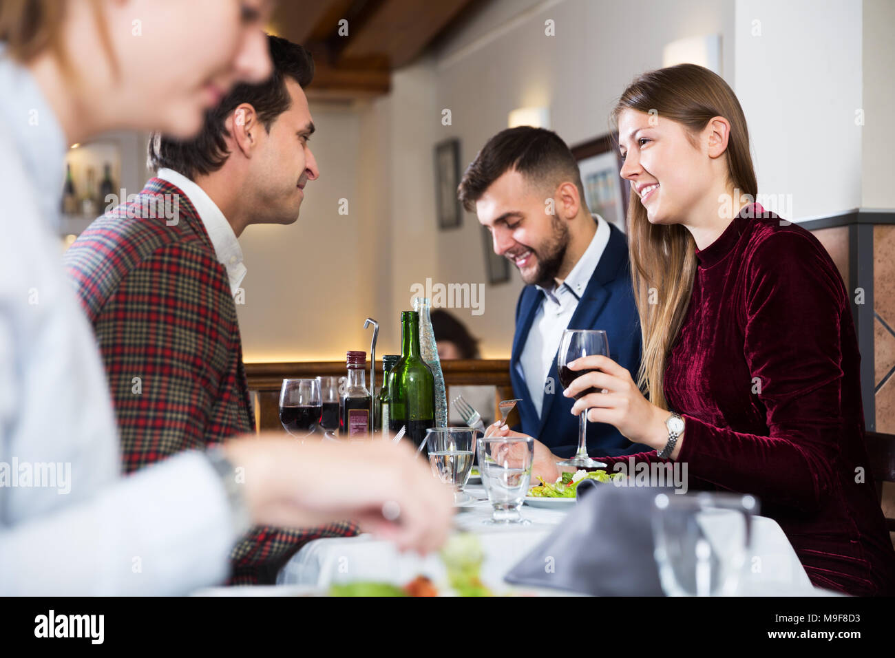 Group of smiling friends having dinner and drinking red wine at ...