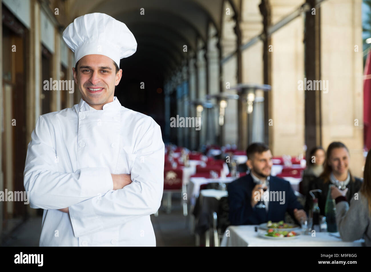 Portrait of professional chef on background with restaurant guests ...