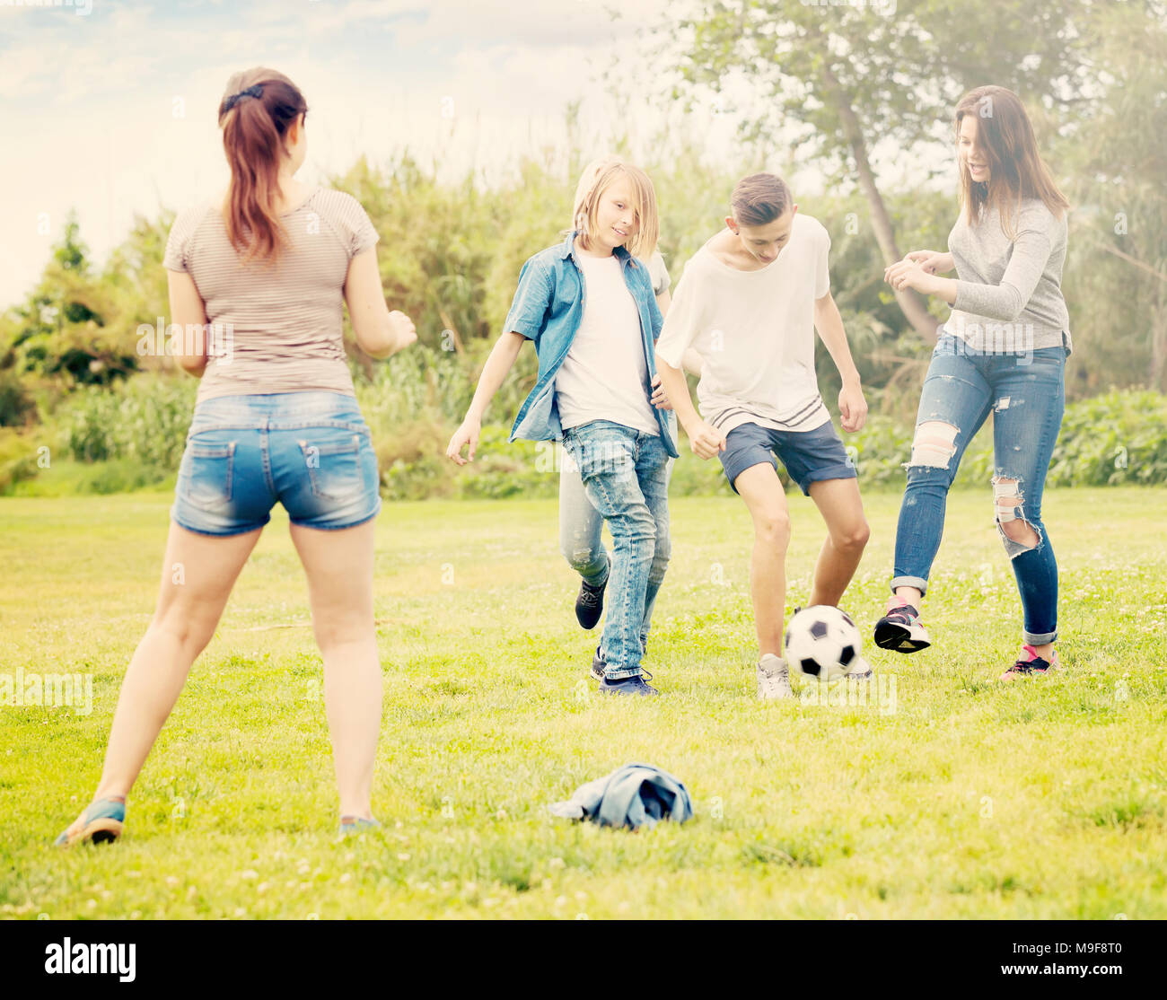 Group of cheerful active teenagers happily playing football together on ...