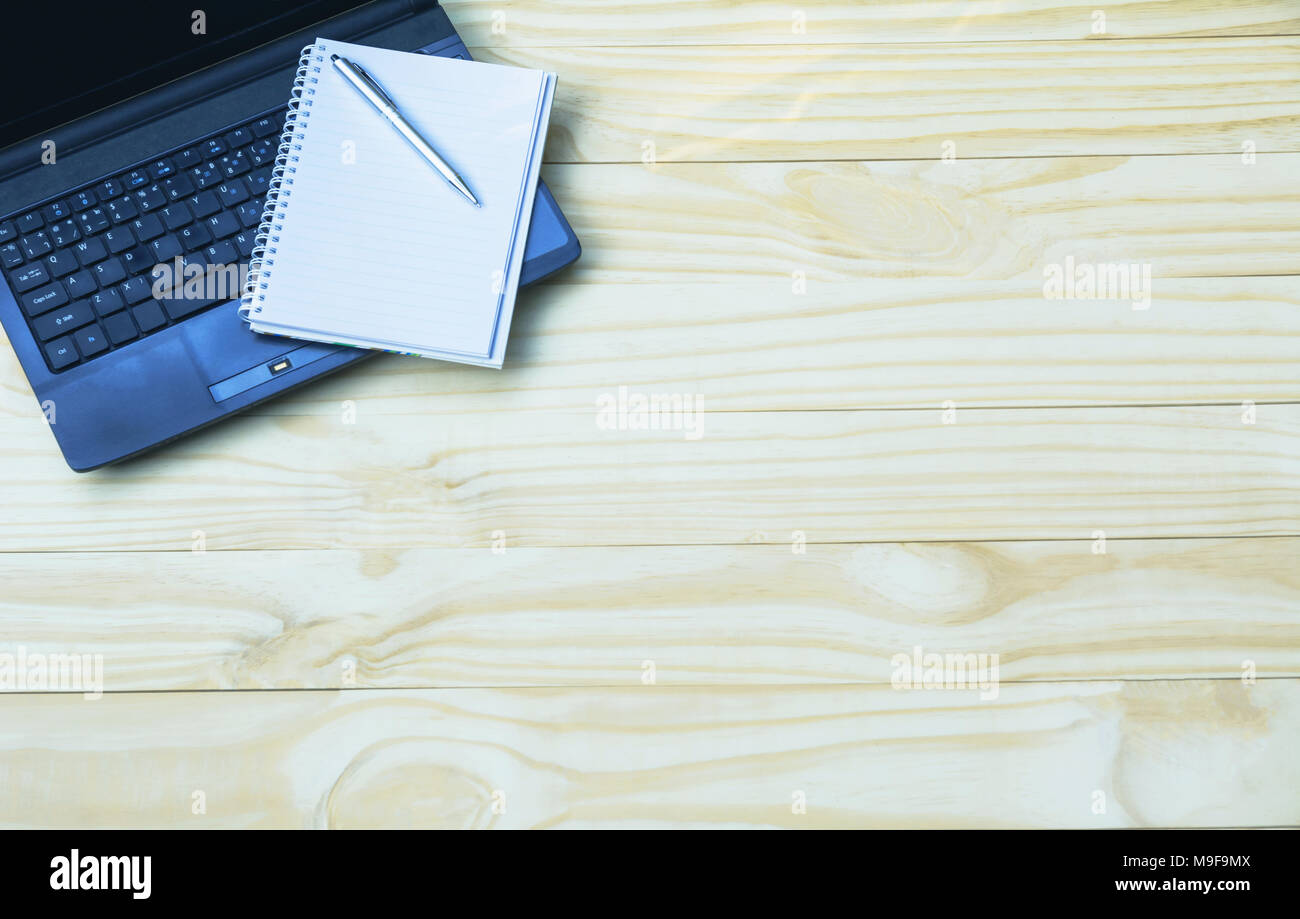 Top view of laptop with open book. Laptop with book open on wooden ...