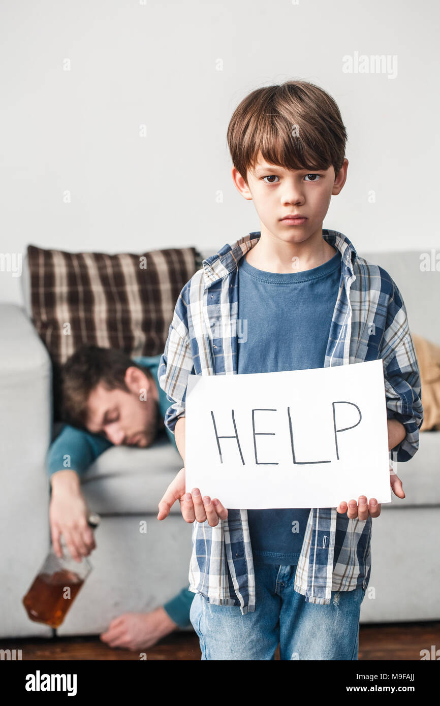 Boy and father alcoholic at home son standing holding help sign while ...