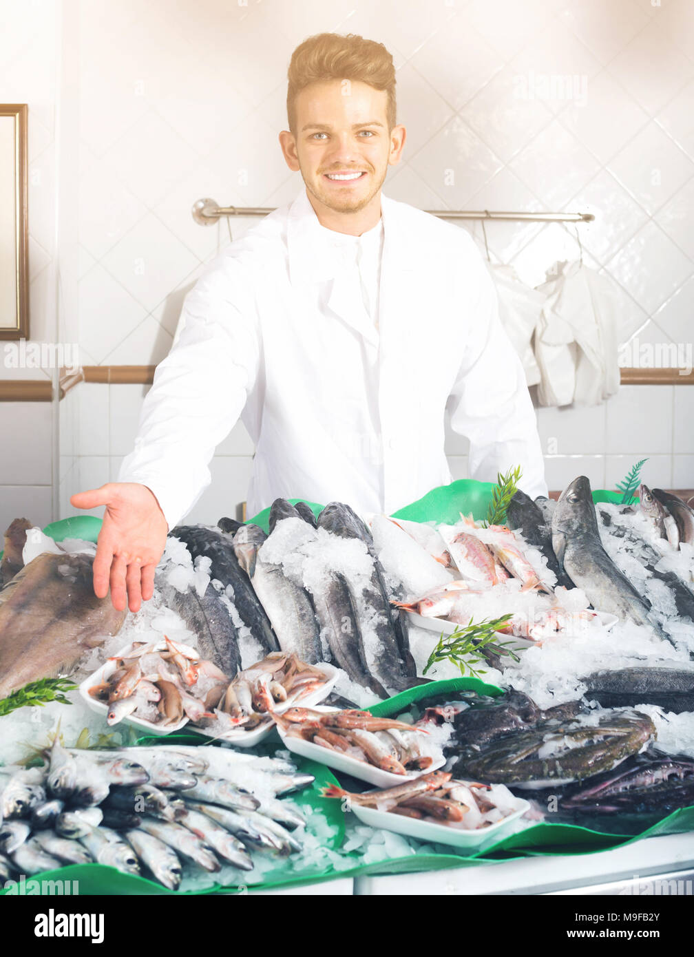 Happy guy selling chilled fish and seafood in store Stock Photo - Alamy