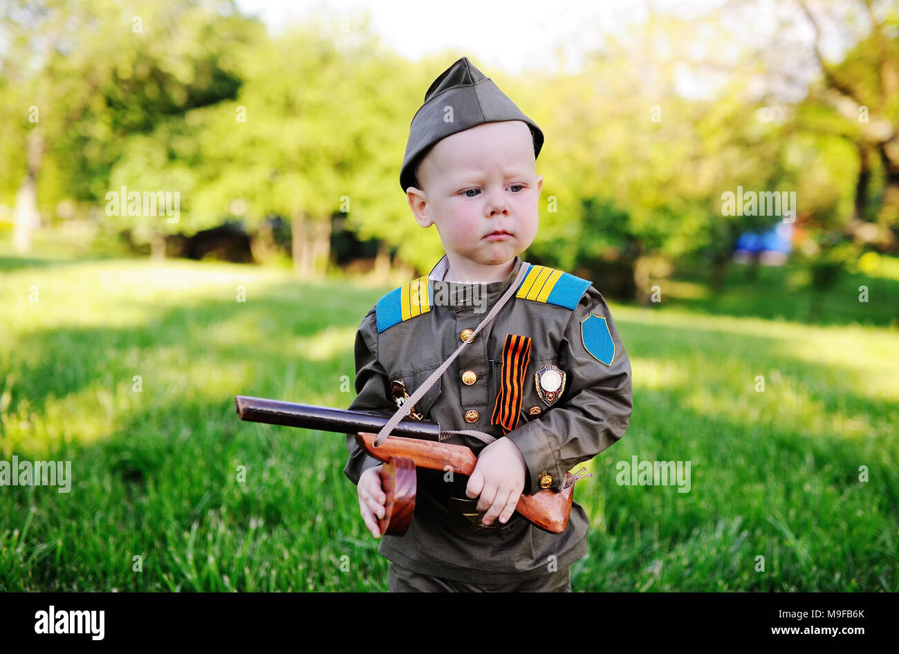 baby boy in uniform with St. George ribbon and with a toy gun on the ...