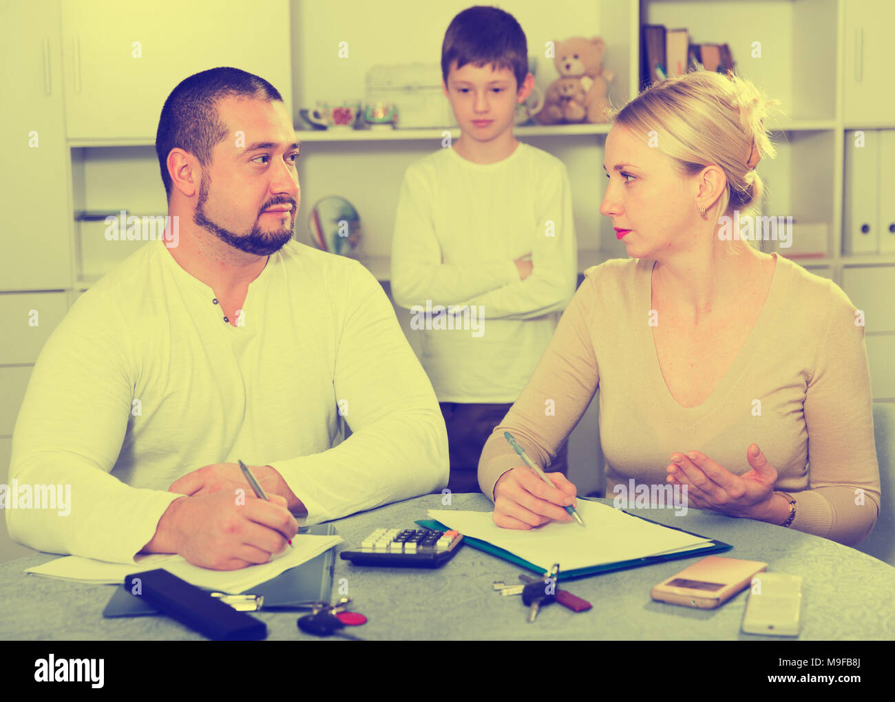 Parents calculating family budget and utility at home while son ...