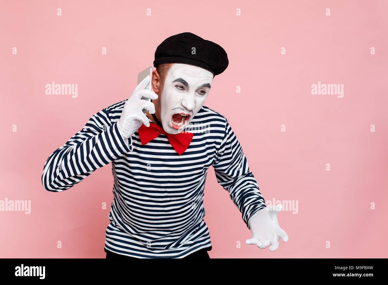 Angry man in striped sweater, gloves call in smartphone, shouting ...
