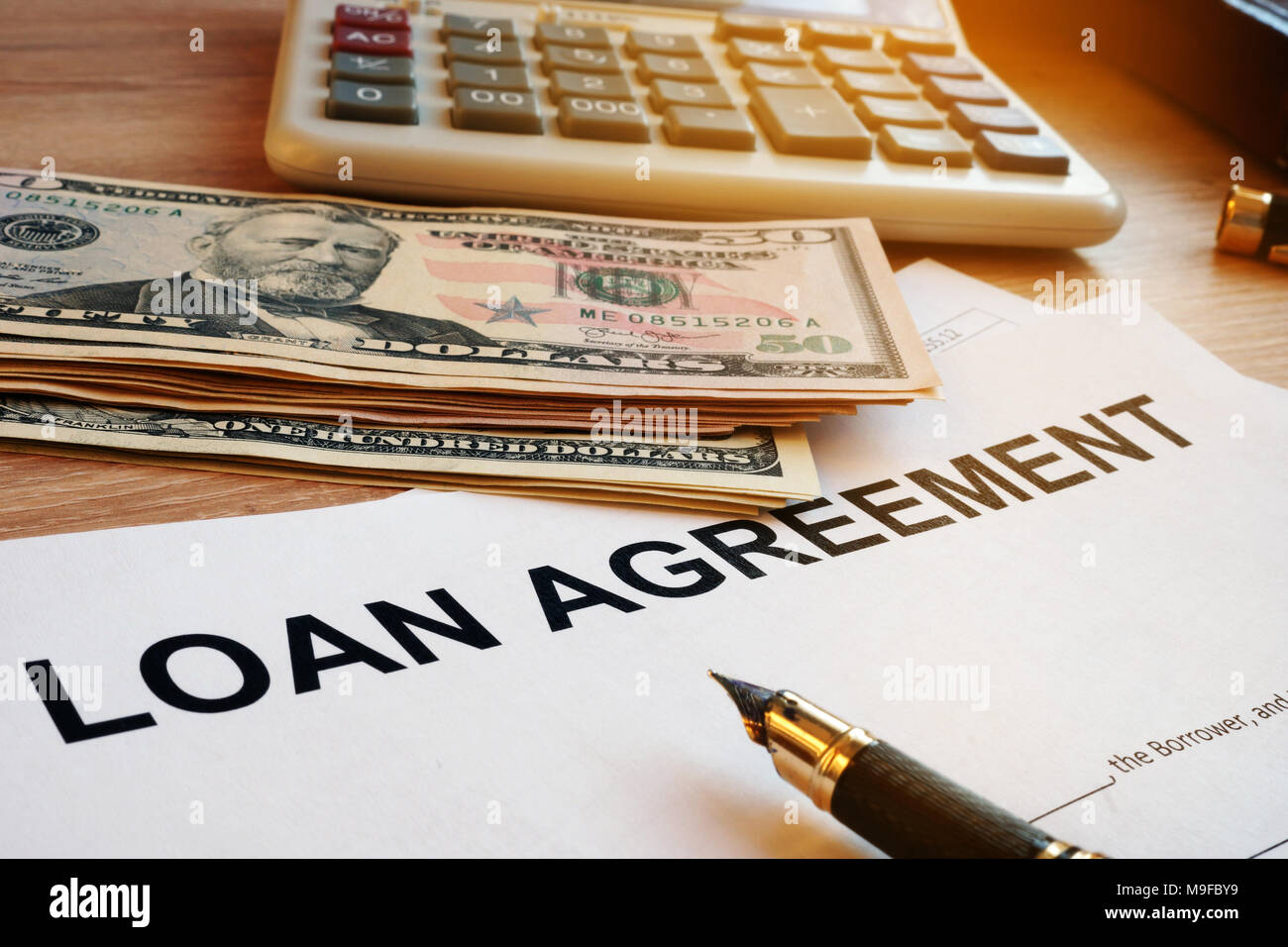 Loan agreement, money and calculator on a desk Stock Photo - Alamy