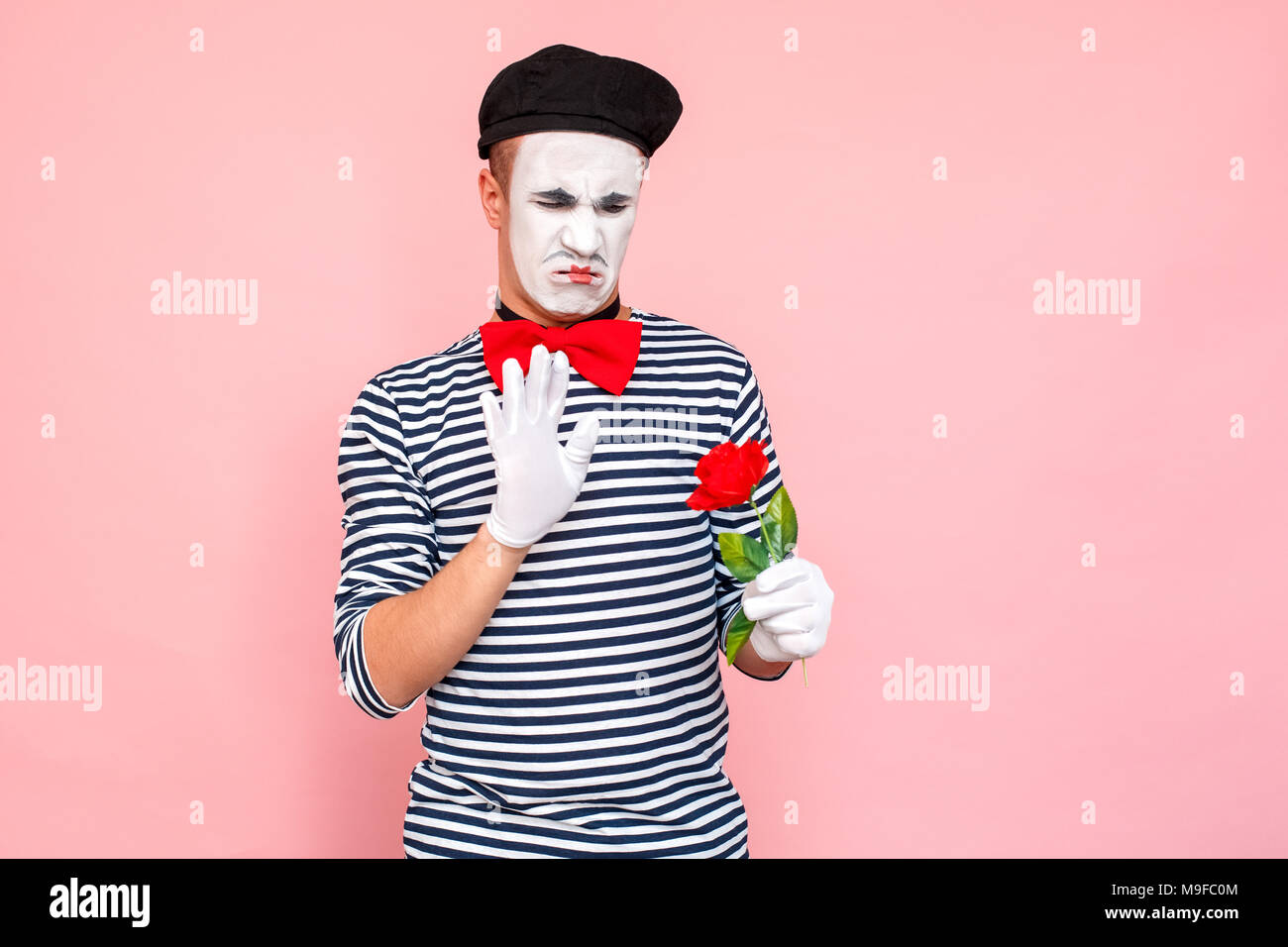 Man holding red rose but does not like roses. Clown, artist , mime ...