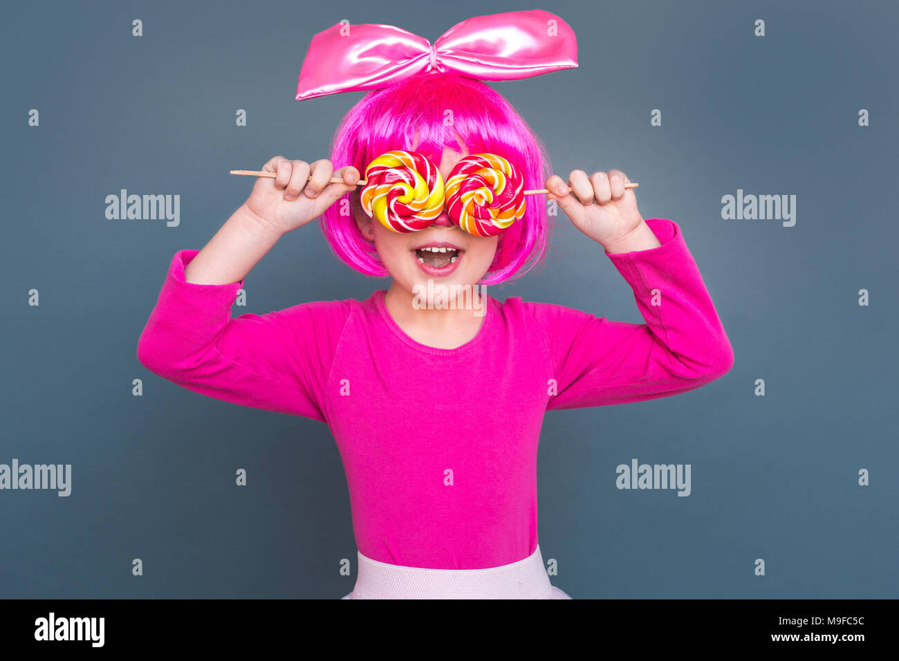 Girl clown in pink wig and bow closed eyes two candies and toothy ...