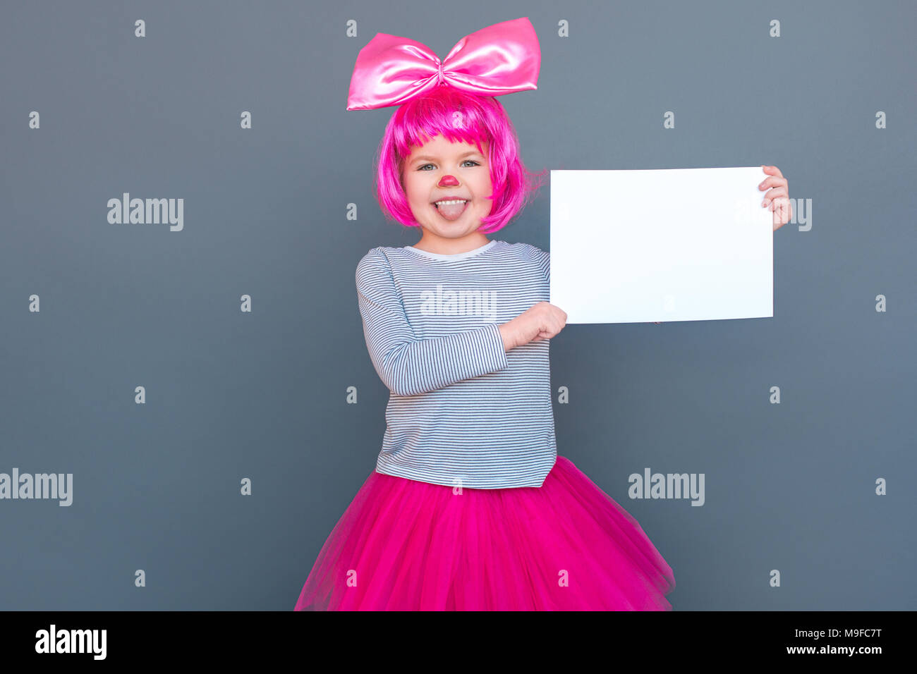 Attractive little girl in clown costume holding white desk. Studio shot ...