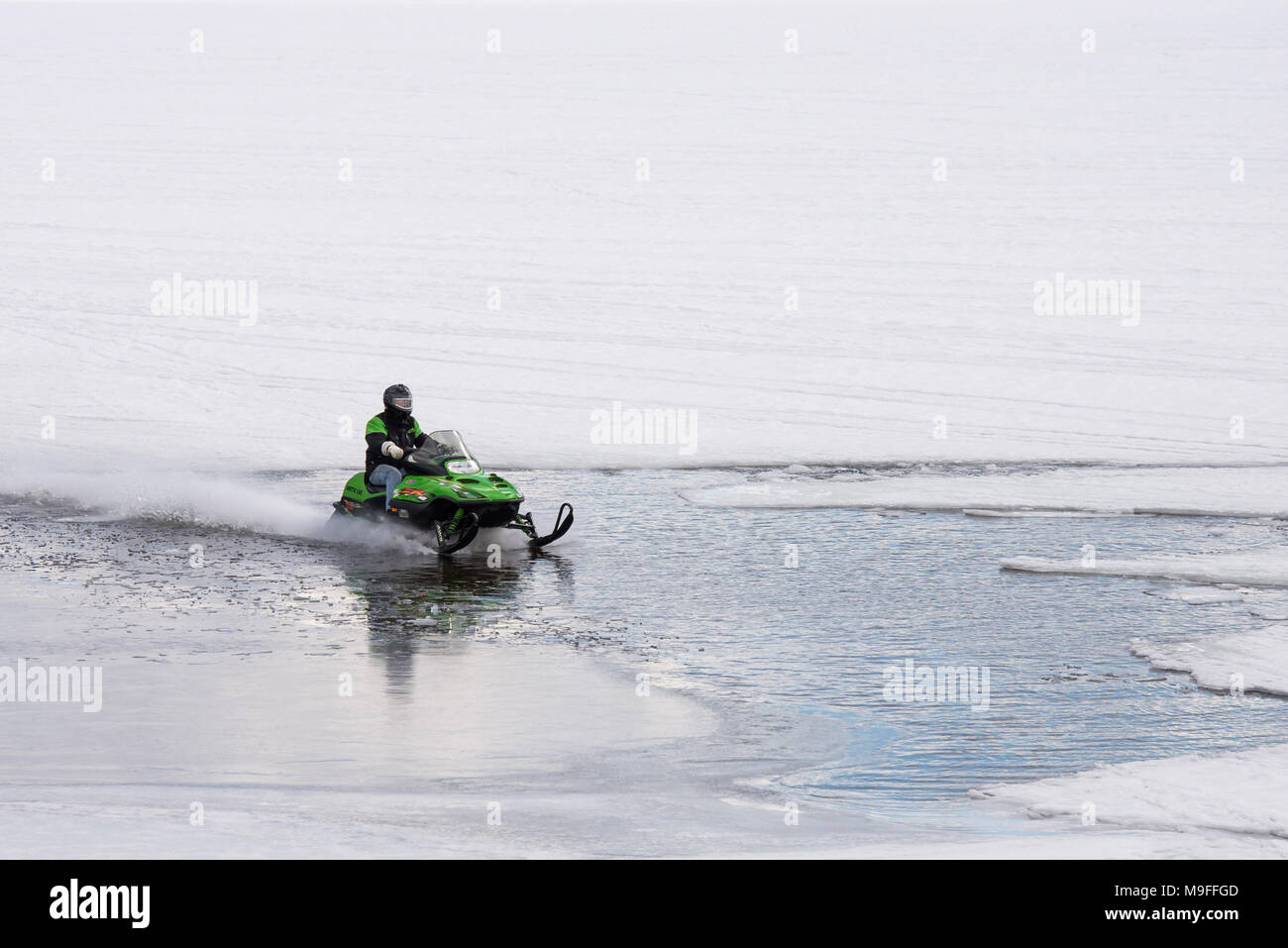 Snowmobile racing across an open patch of water on Lake Pleasant, NY in ...