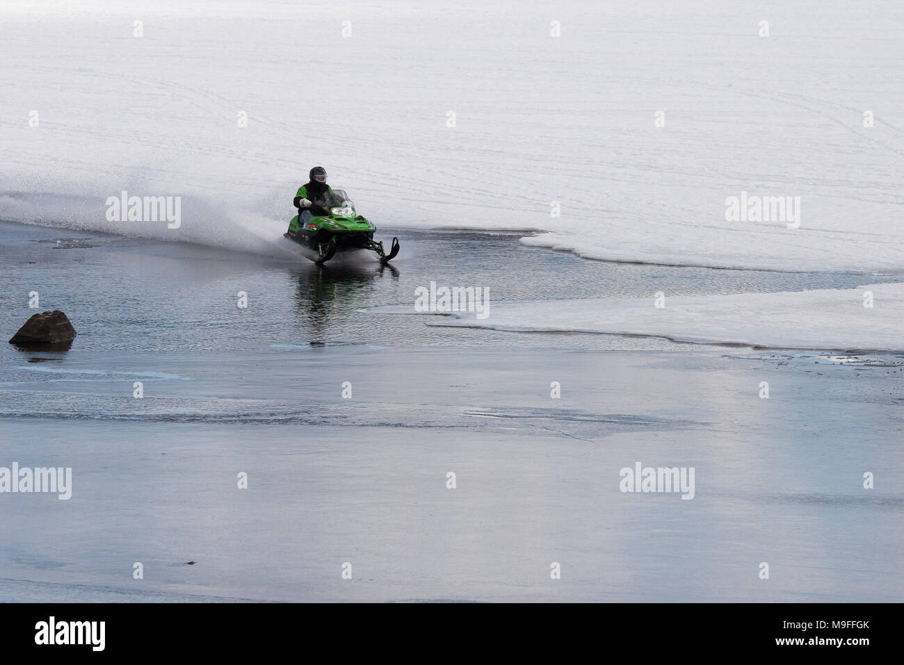 Snowmobile racing across an open patch of water on Lake Pleasant, NY in ...