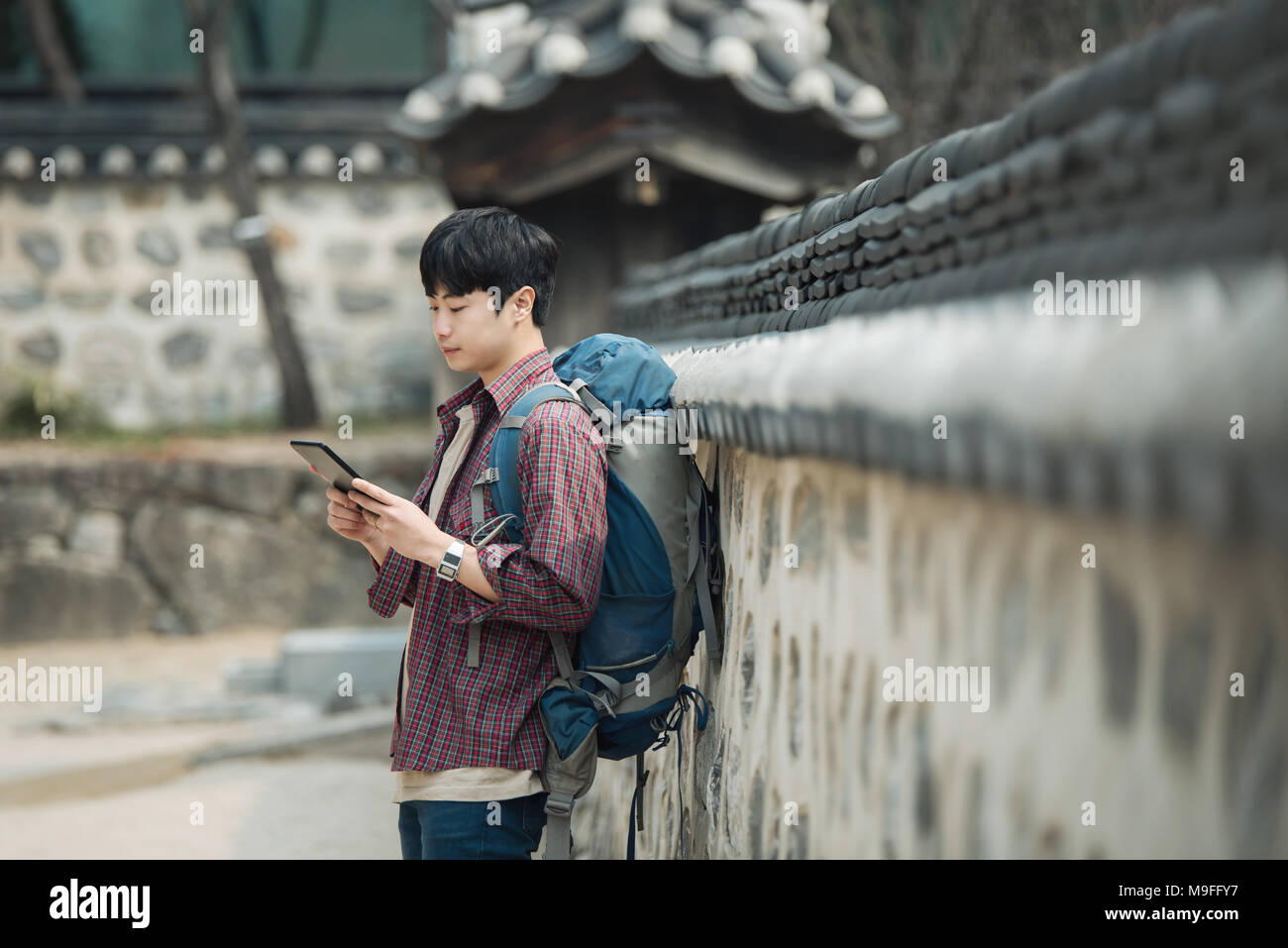 A young man backpacking in Korea. Using a tablet computer leaning ...
