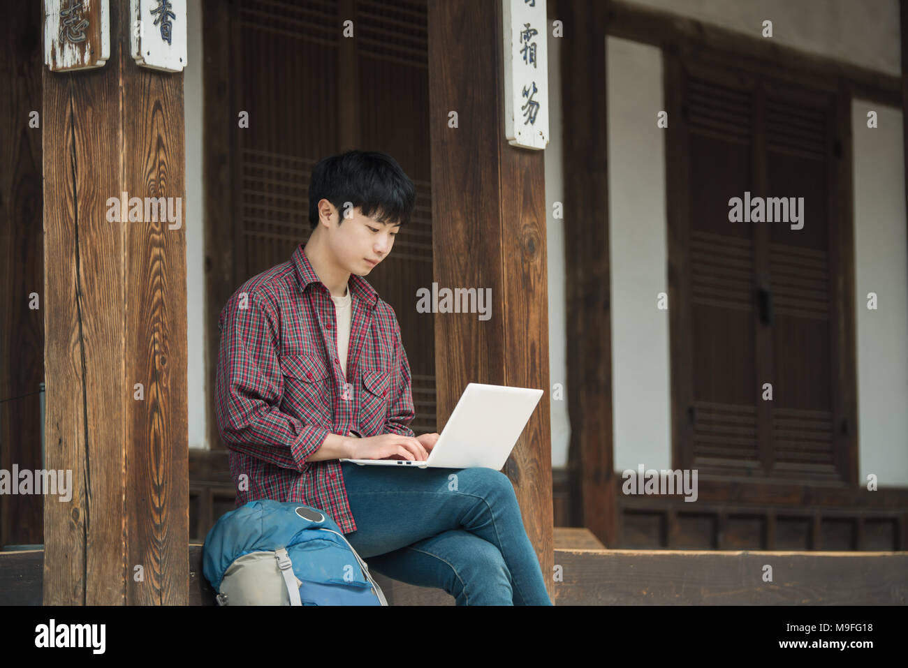 A young man backpacking in Korea. using a laptop sitting in a Korean ...