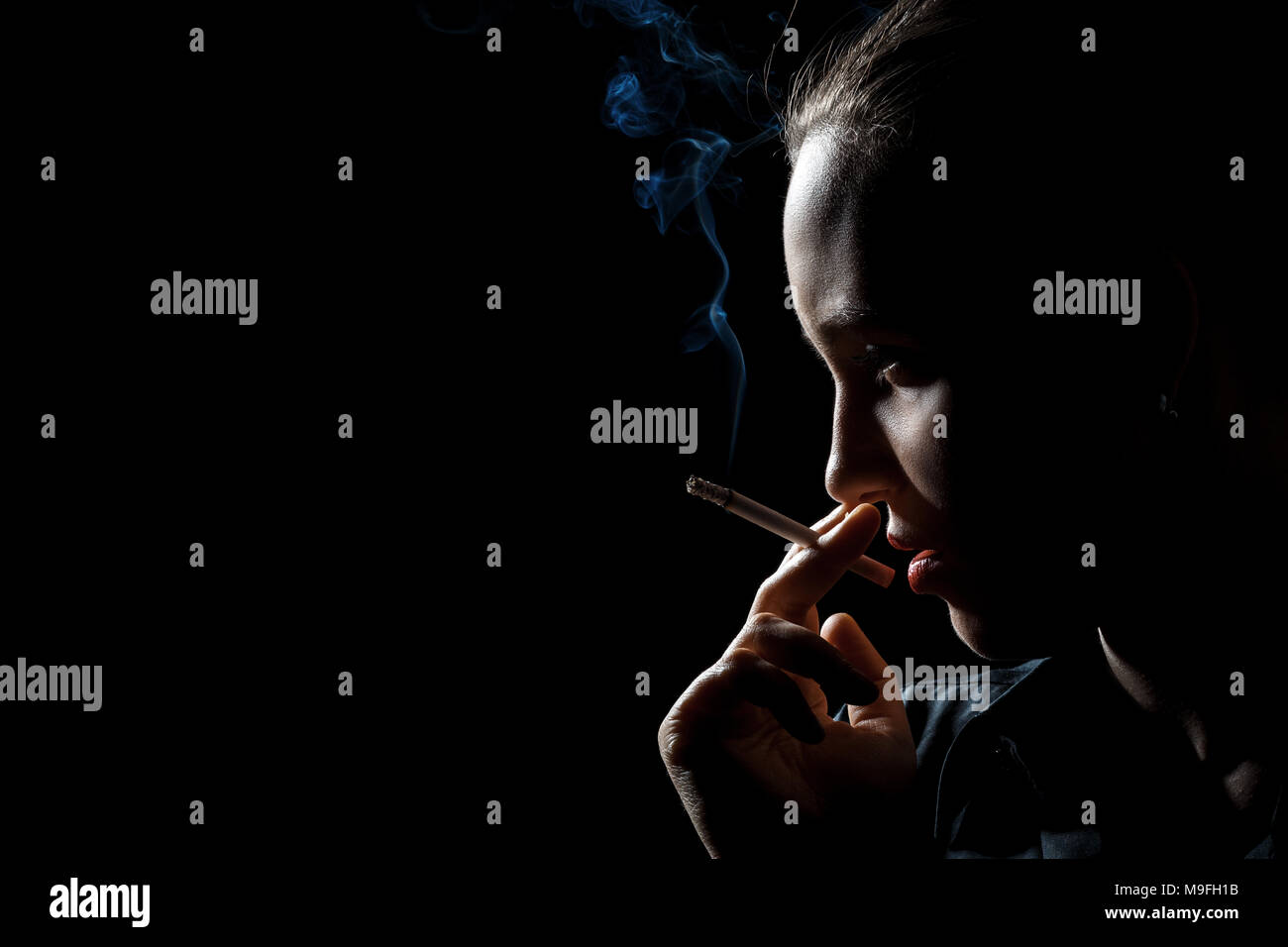 serious woman smoking cigarette on black background, profile view Stock ...