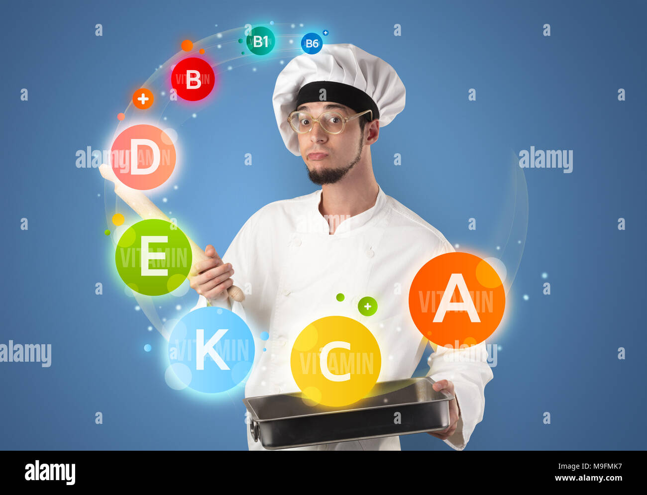 Handsome cook with kitchen instruments and vitamin concept Stock Photo ...