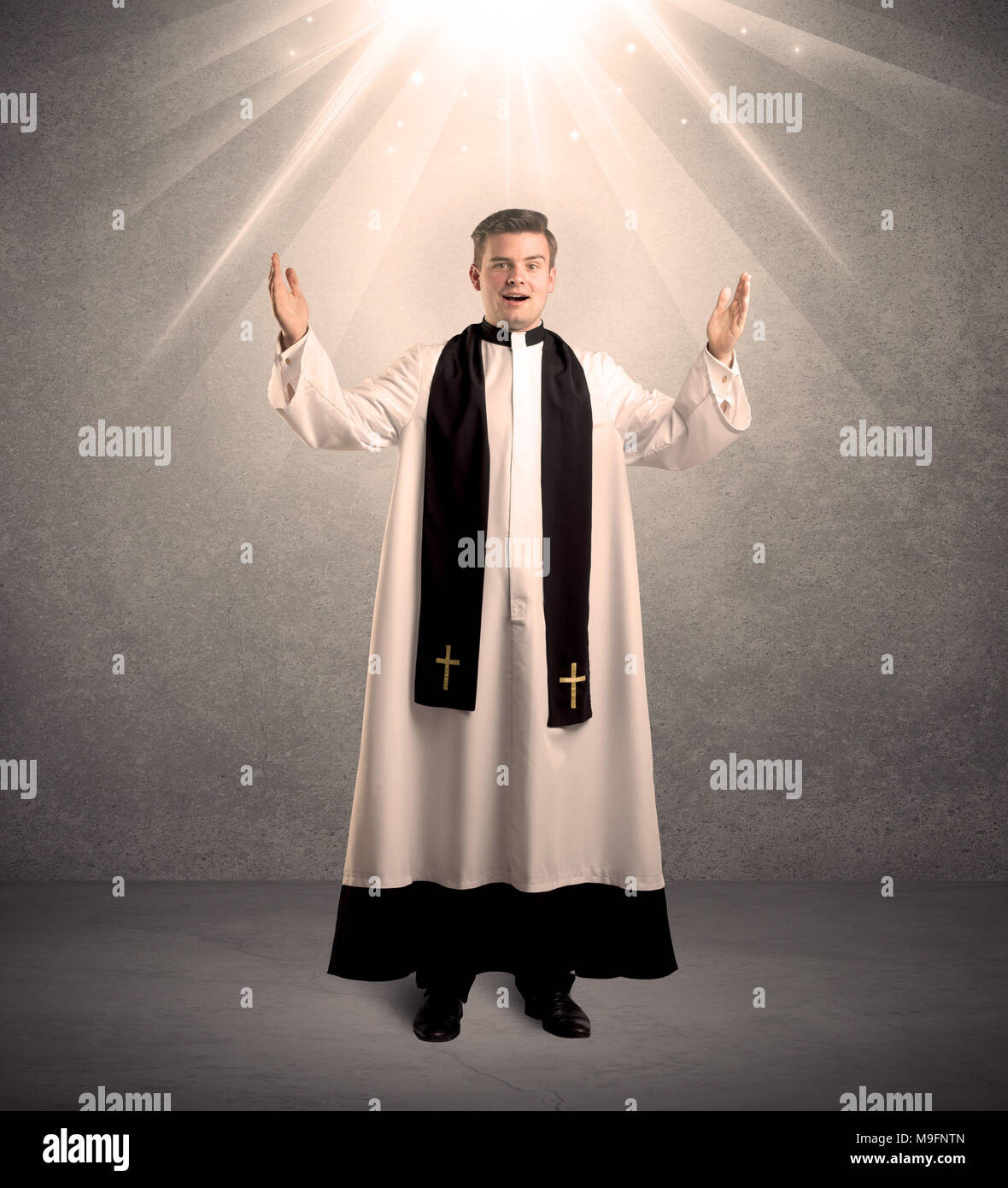 A male religious young priest in black and white dress giving his ...