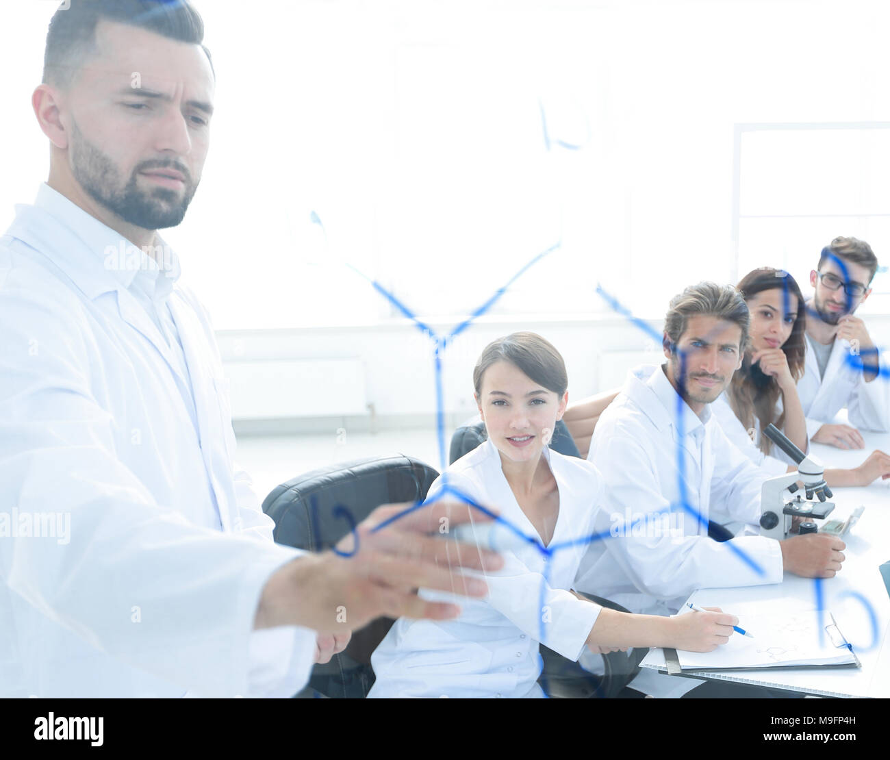 from behind the glass. a scientist standing near the blackboard in the ...