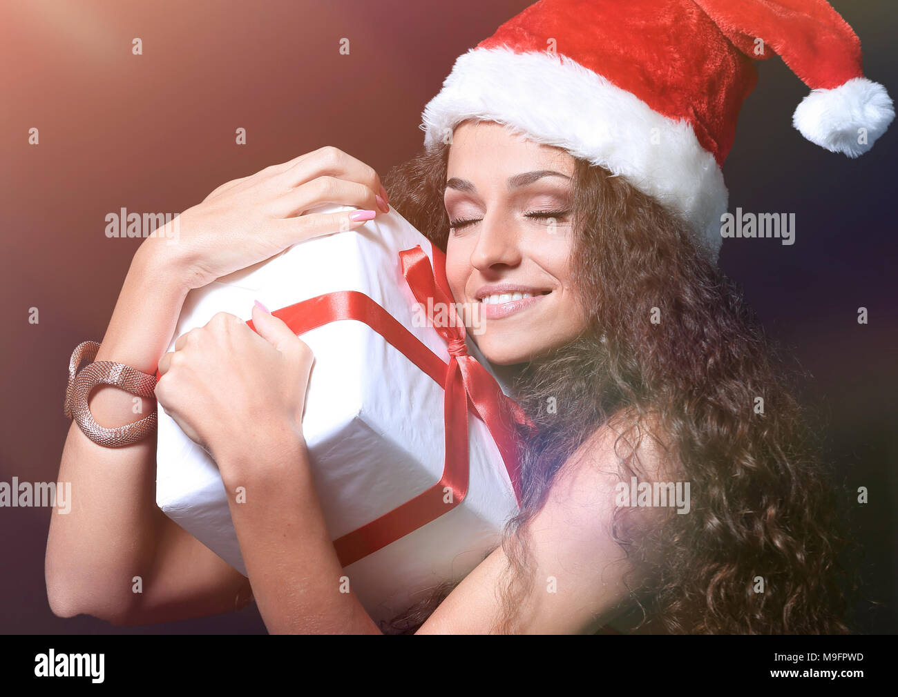 Smiling cheerful woman in red dress holding a gift isolated on black ...