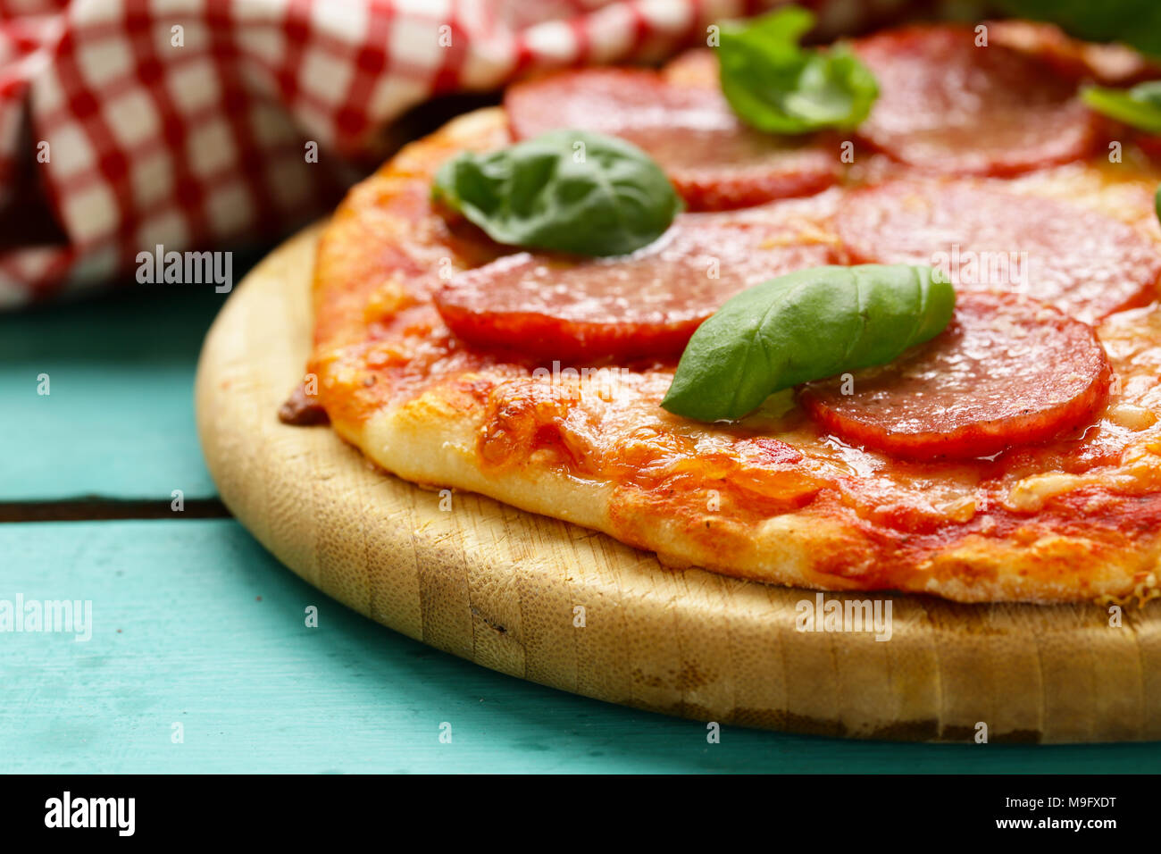 pepperoni pizza with fresh basil on a wooden background Stock Photo - Alamy