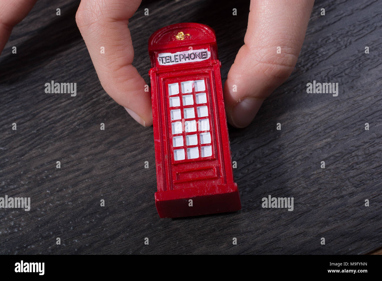 Hand holding a phone booth on a brown background Stock Photo - Alamy