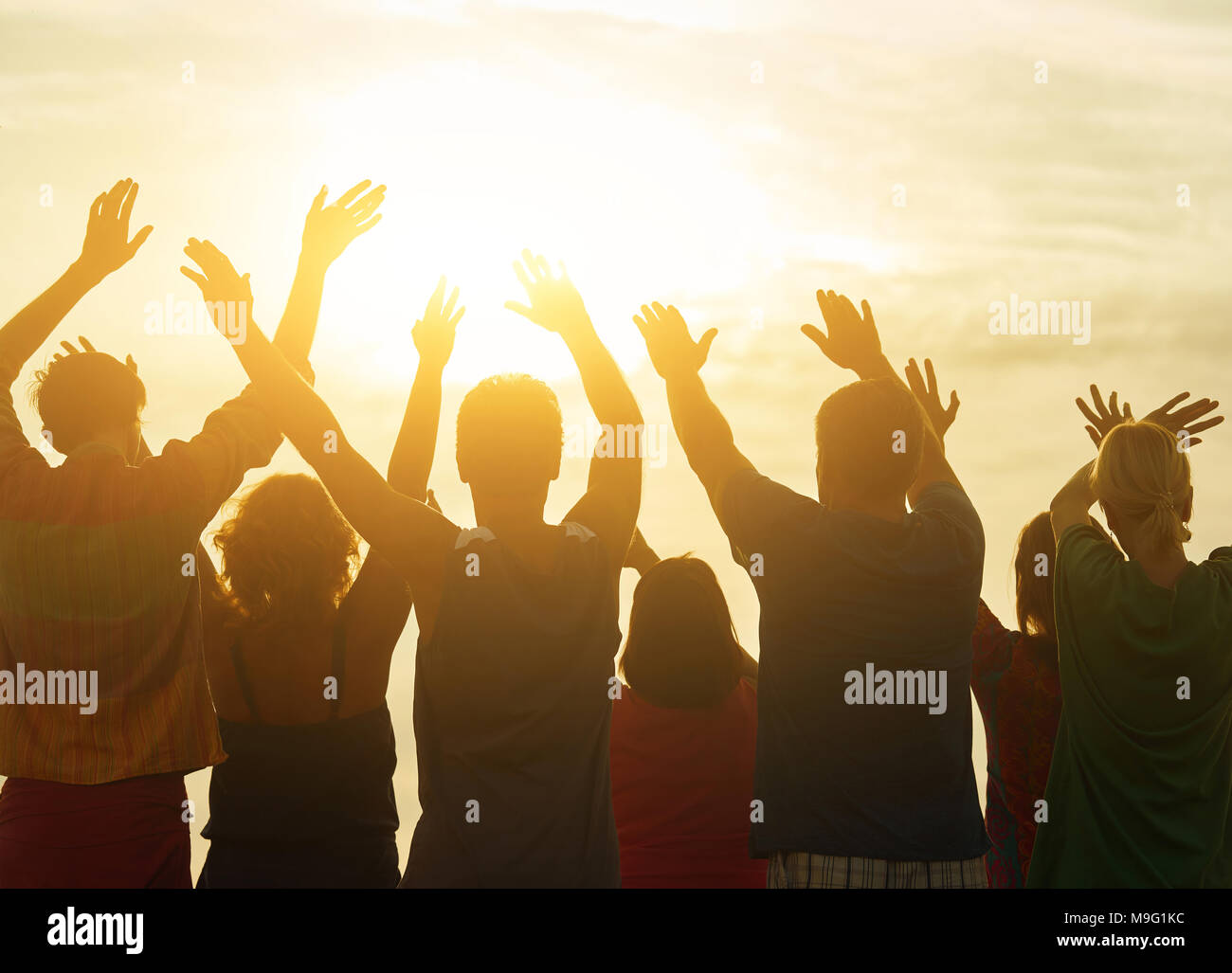 Hands up against sunset background. Bright sunshine, people from behind ...