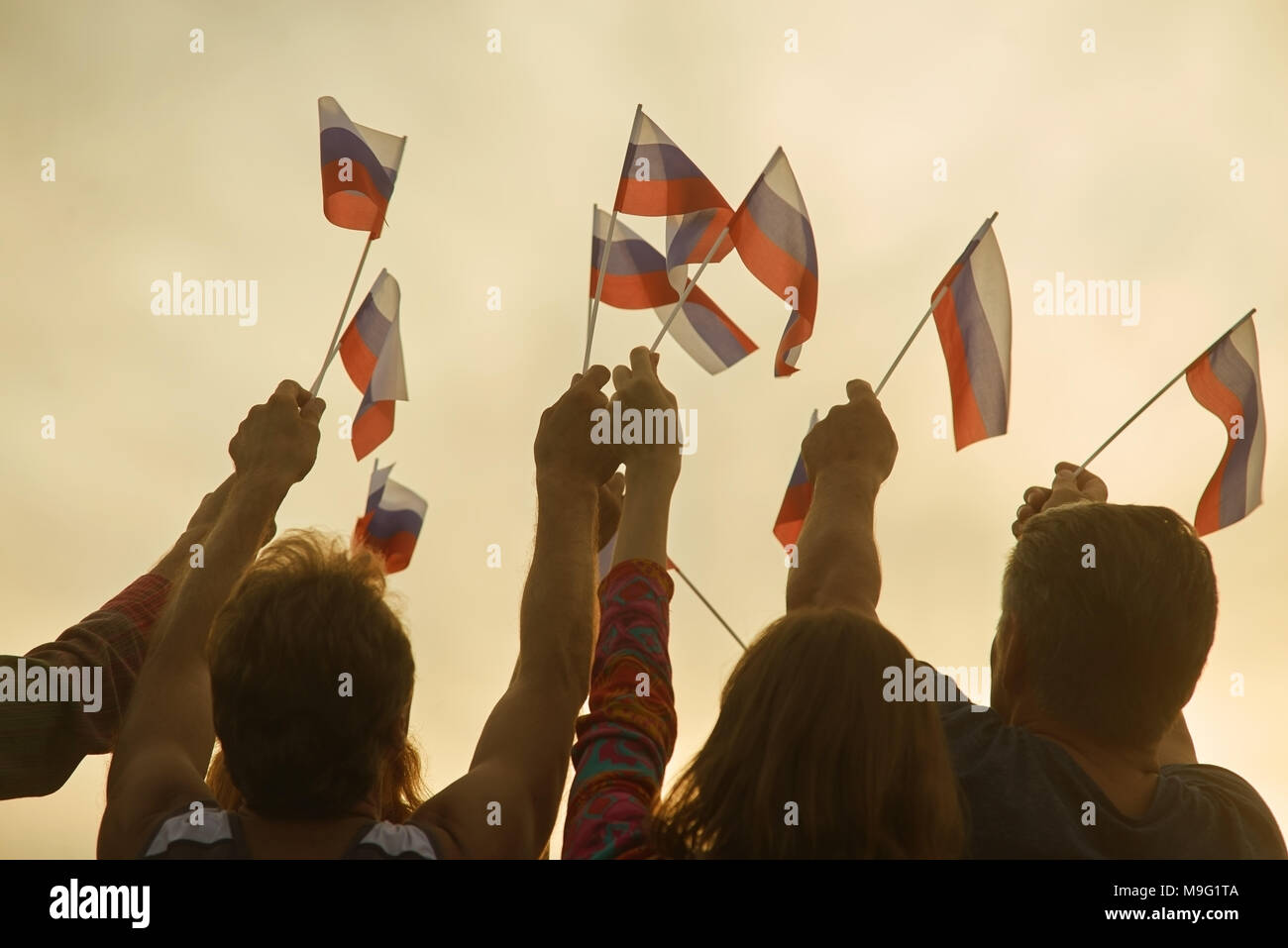 Russian people's hands with flags. Bright evening sky at the down Stock ...