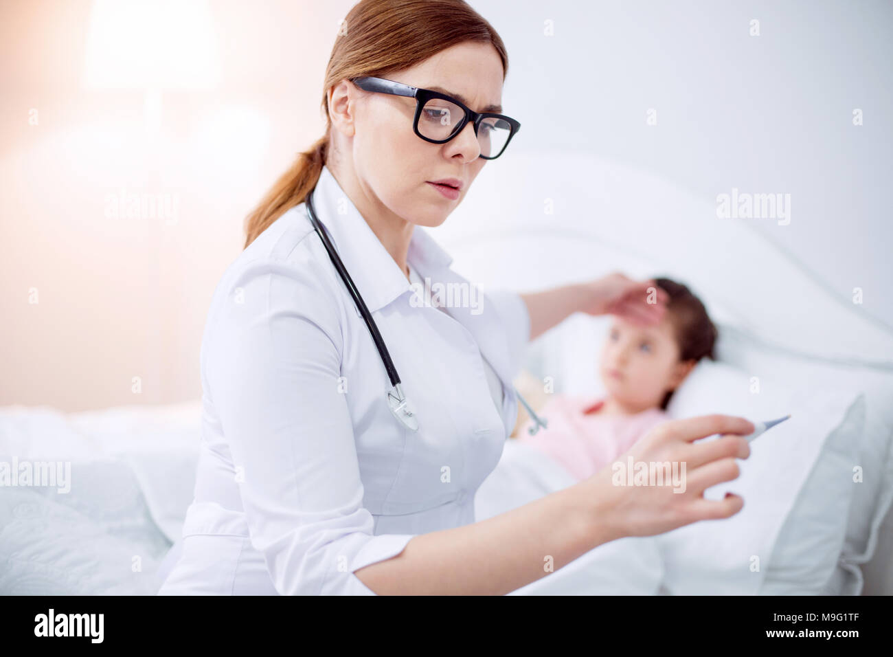 Concerned female doctor using thermometer Stock Photo - Alamy