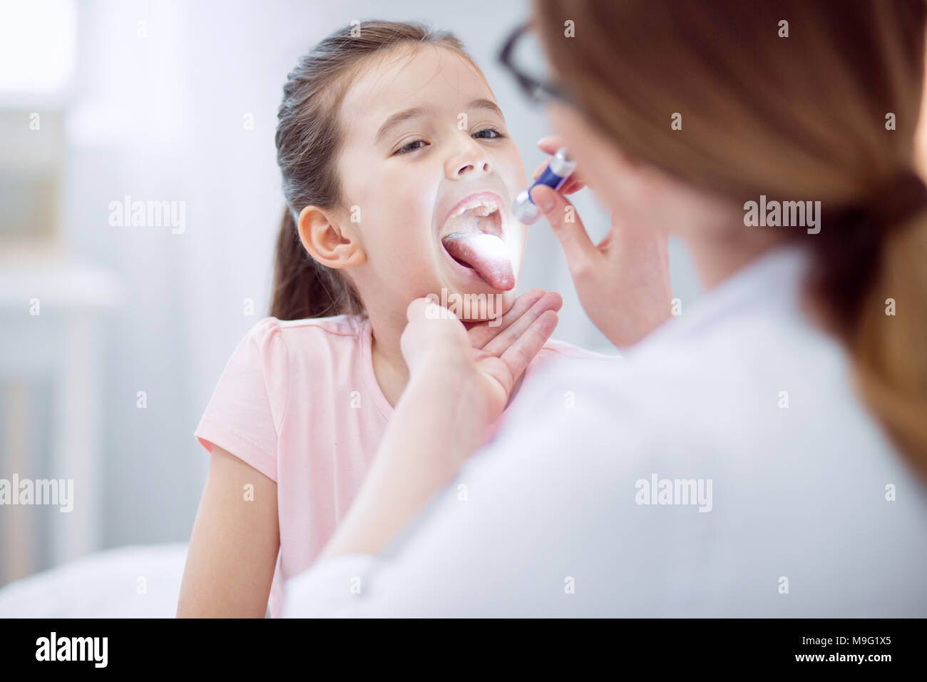Ambitious female doctor checking girls throat Stock Photo - Alamy