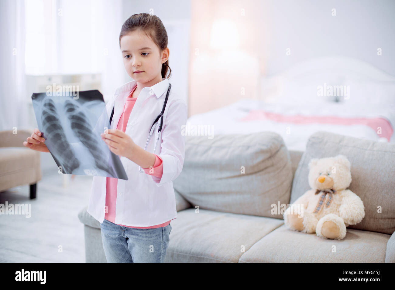 Concentrated thoughtful girl examining radiography Stock Photo - Alamy