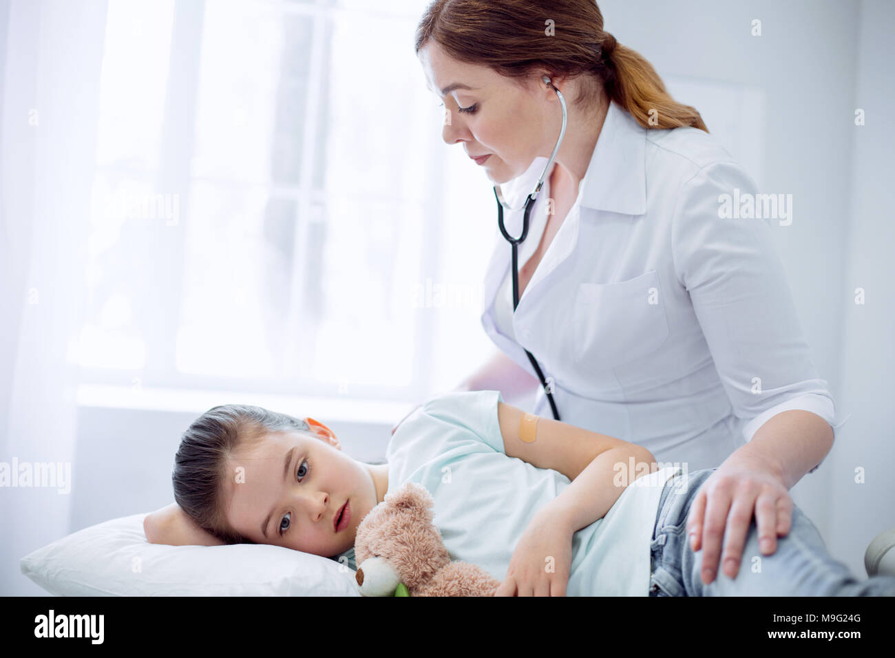 Professional female doctor soothing ill girl Stock Photo - Alamy