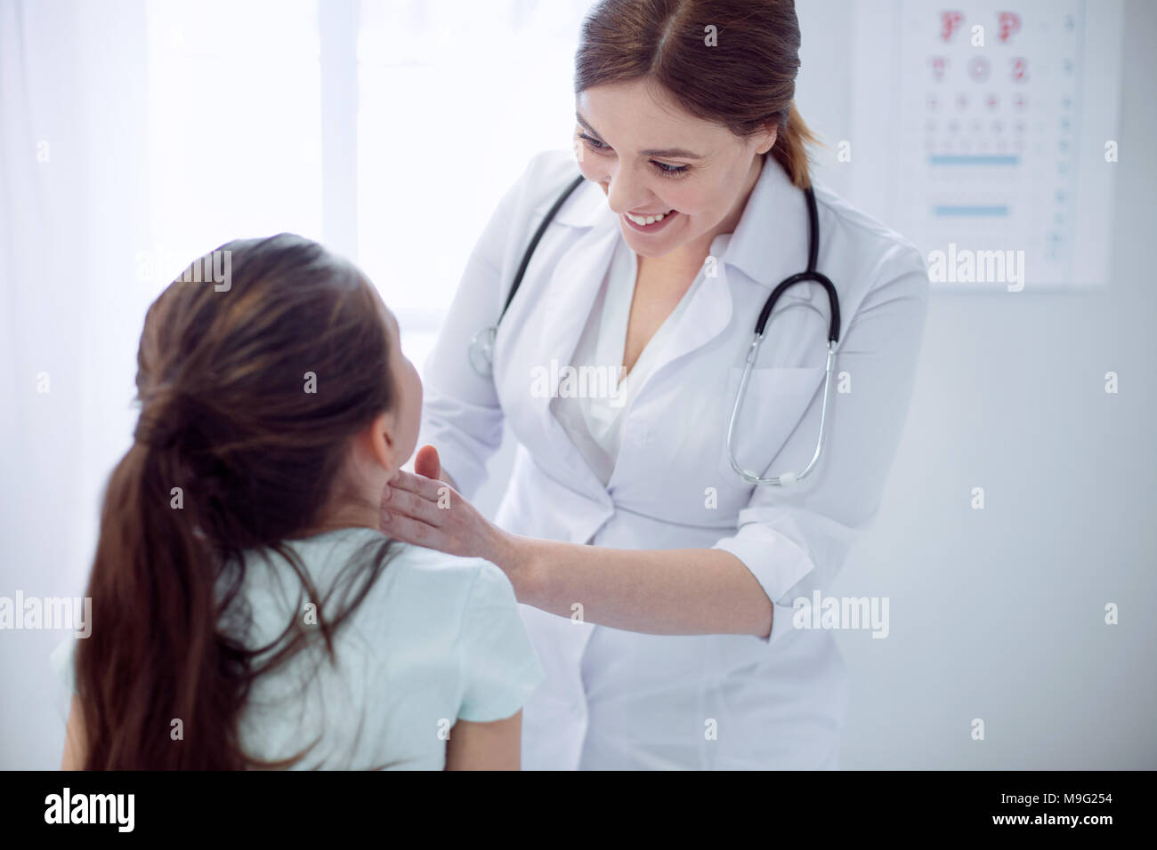 Optimistic female doctor asking girl about her feelings Stock Photo - Alamy