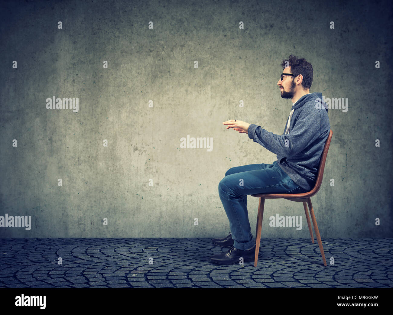 Side view of casual man sitting at invisible table pretending to type ...
