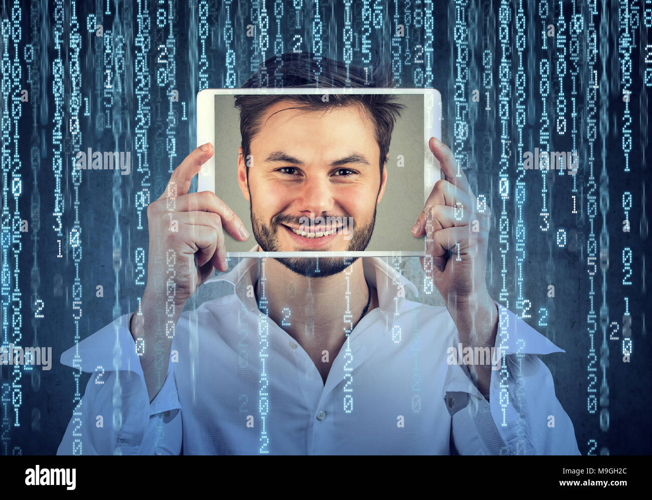 Happy man holding tablet with his face displayed on a screen isolated on binary code background ...