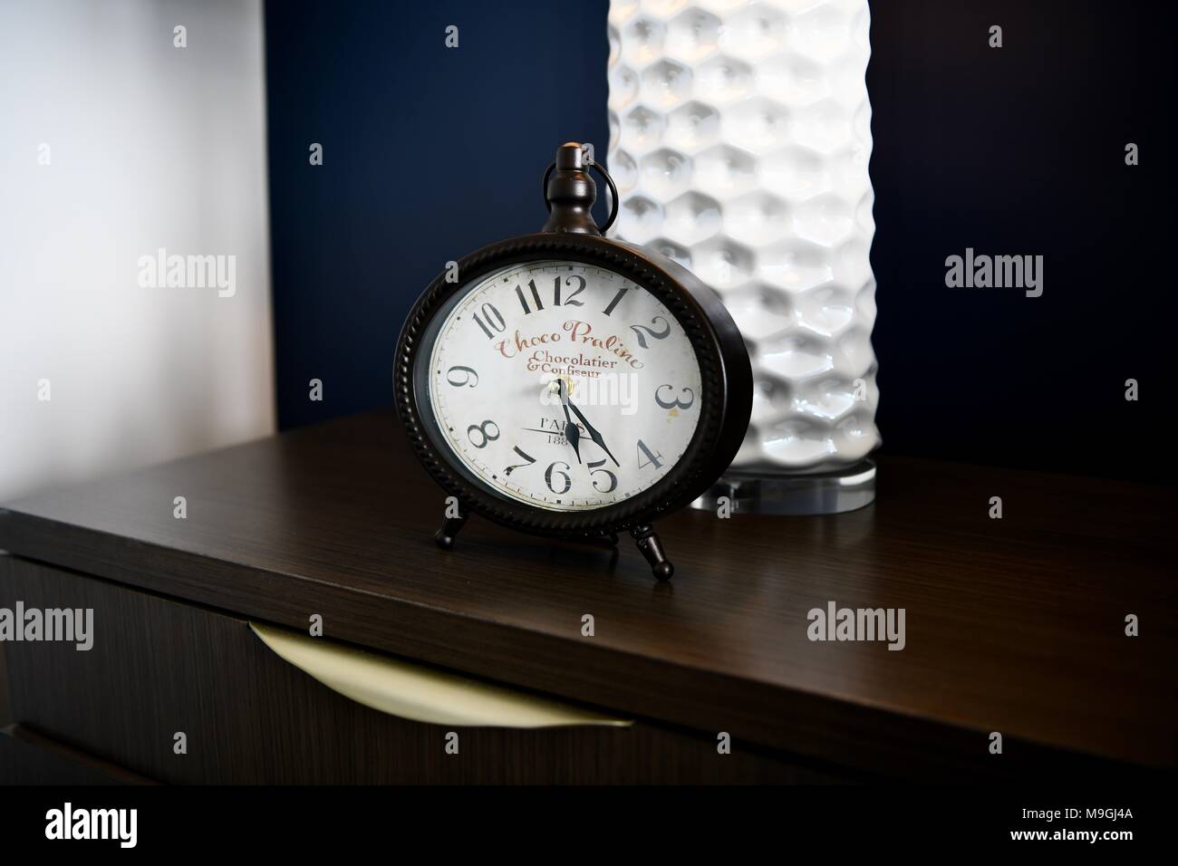 clock on night stand next to bed Stock Photo - Alamy