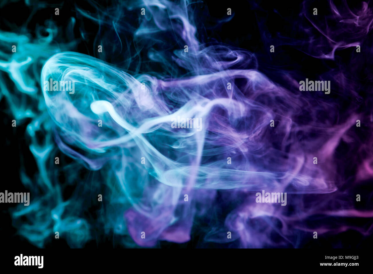 Dense multicolored smoke of blue and purple colors on a black isolated ...