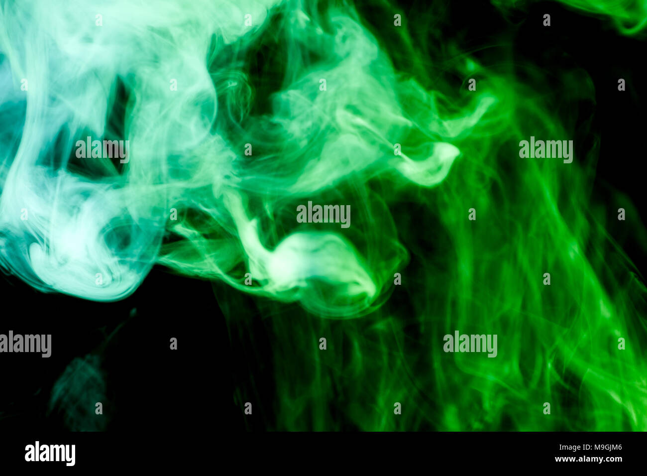 Dense multicolored smoke of green colors on a black isolated background ...
