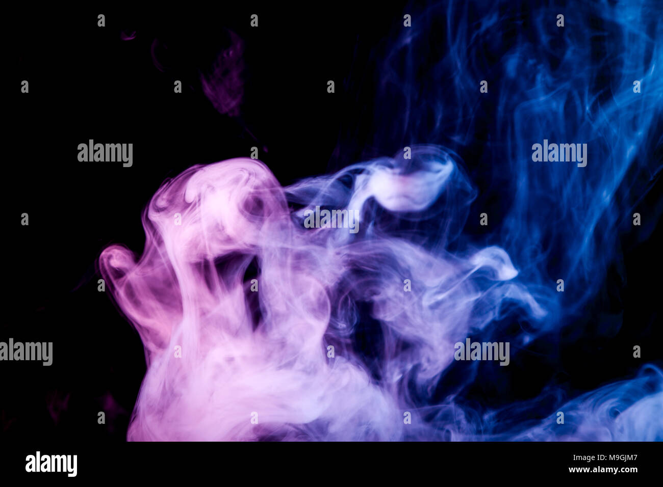 Dense multicolored smoke of blue and purple colors on a black isolated ...